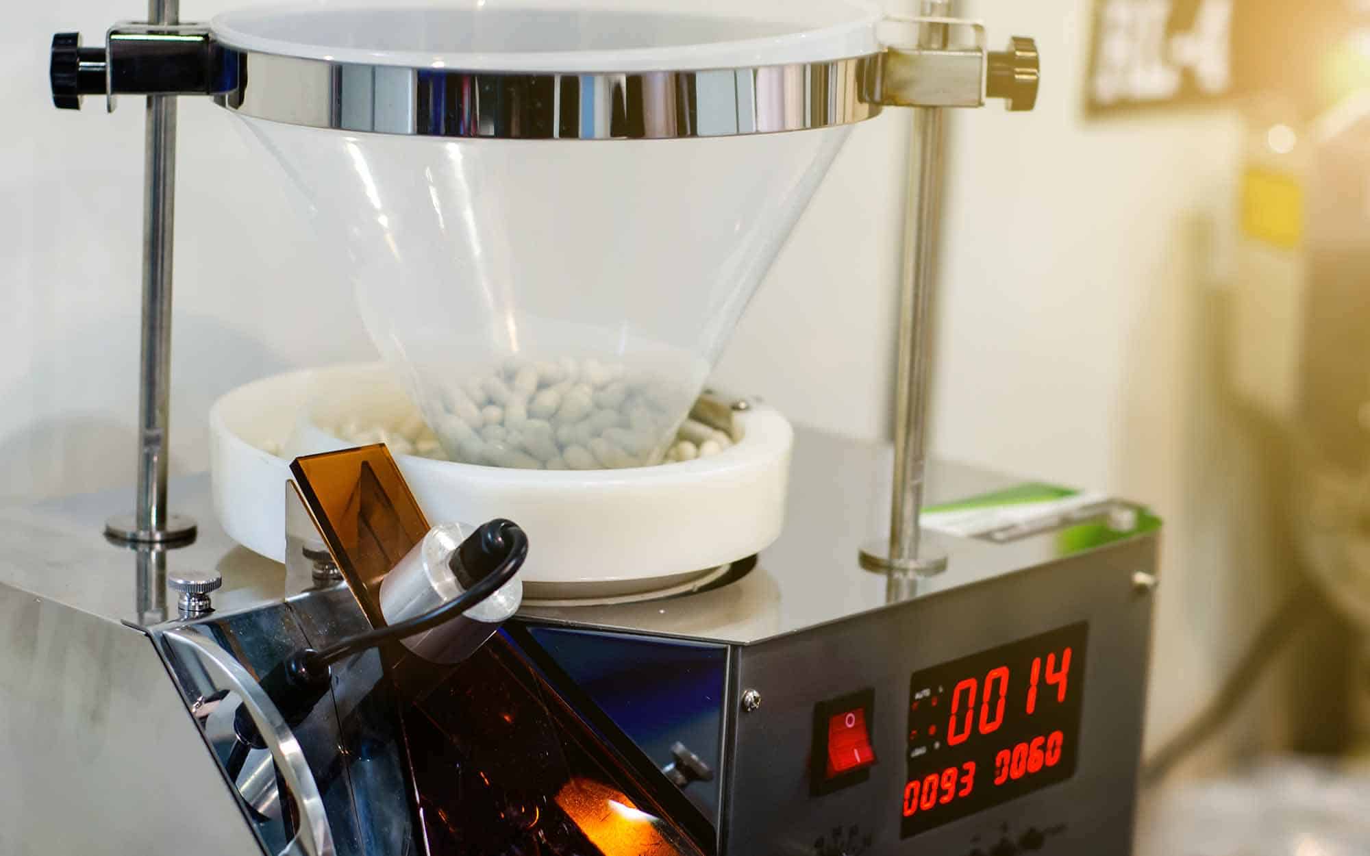 White pills being sorted through a sorting machine - Thomas Packaging